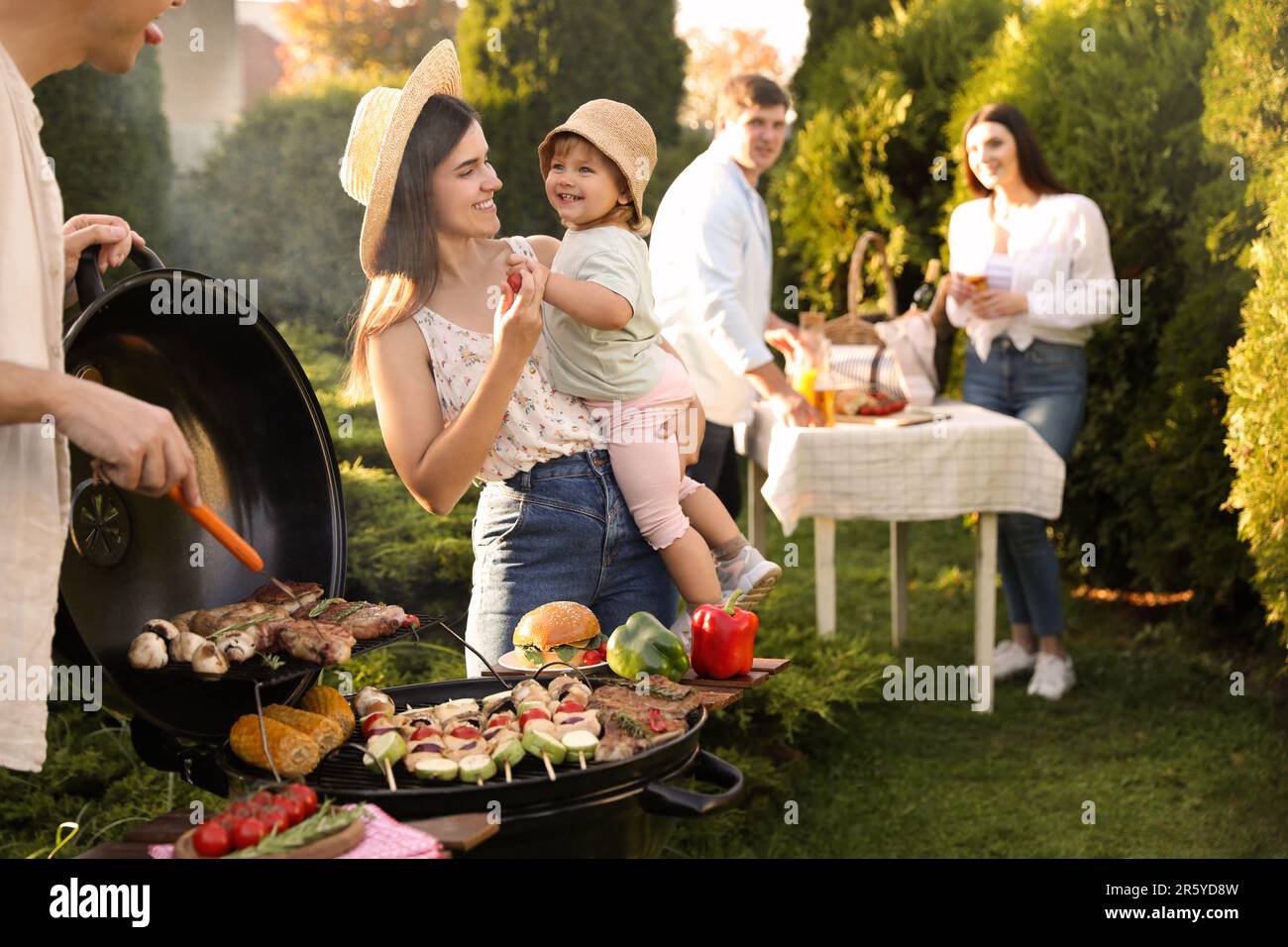 Family with friends having barbecue party outdoors Stock Photo - Alamy