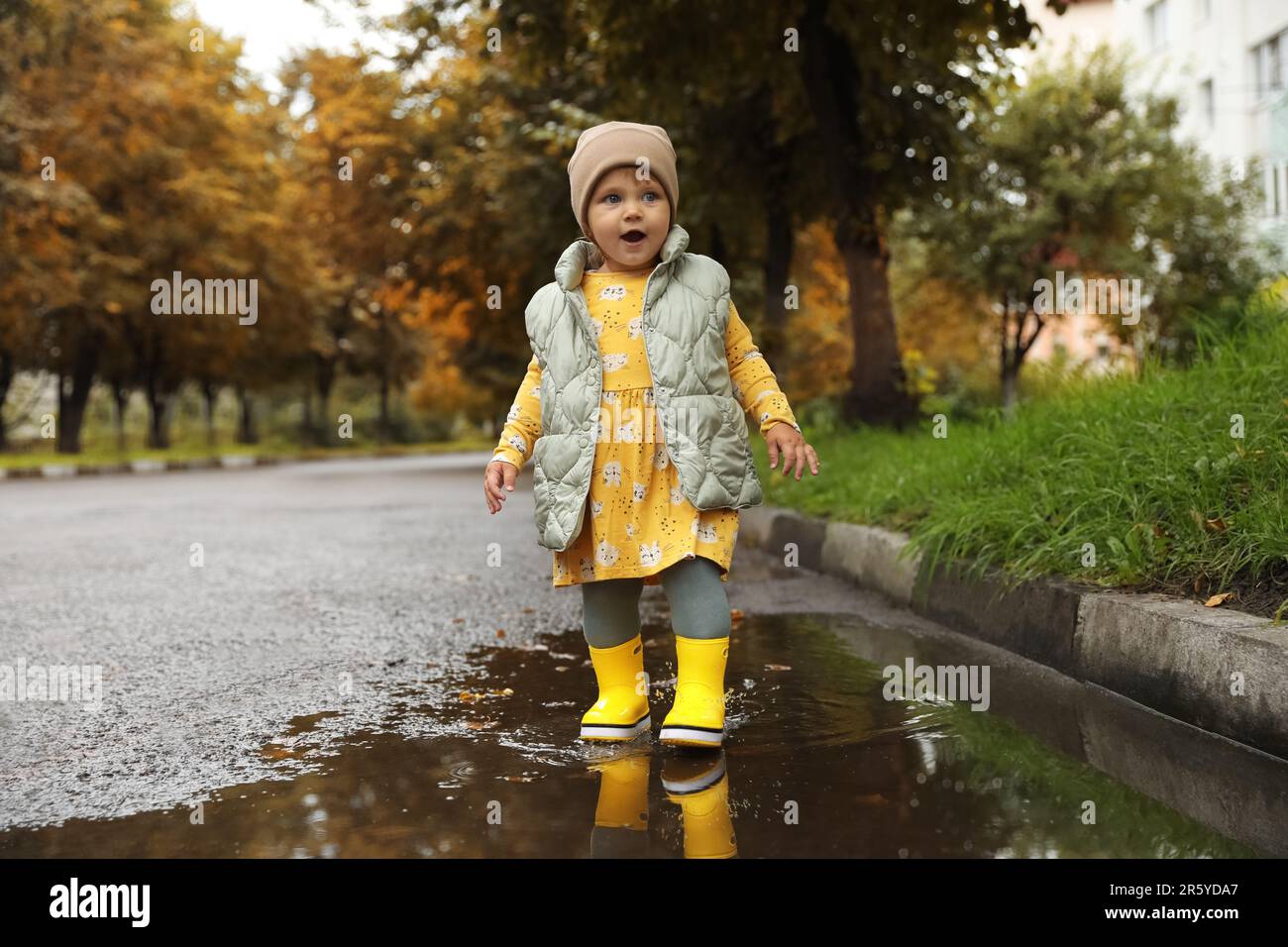 Cute little girl standing in puddle outdoors Stock Photo - Alamy