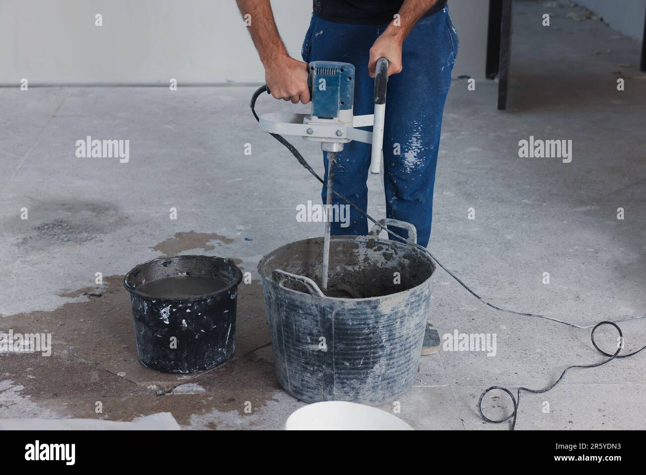 Professional worker mixing cement in bucket indoors, closeup. Tiles ...