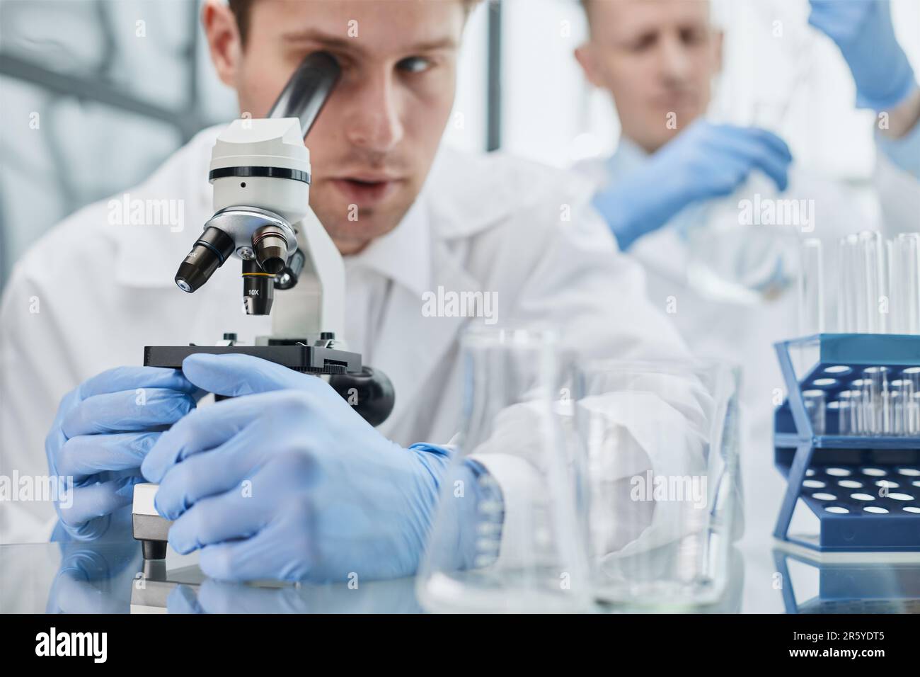 Young scientist looking through a microscope in a laboratory. Young ...