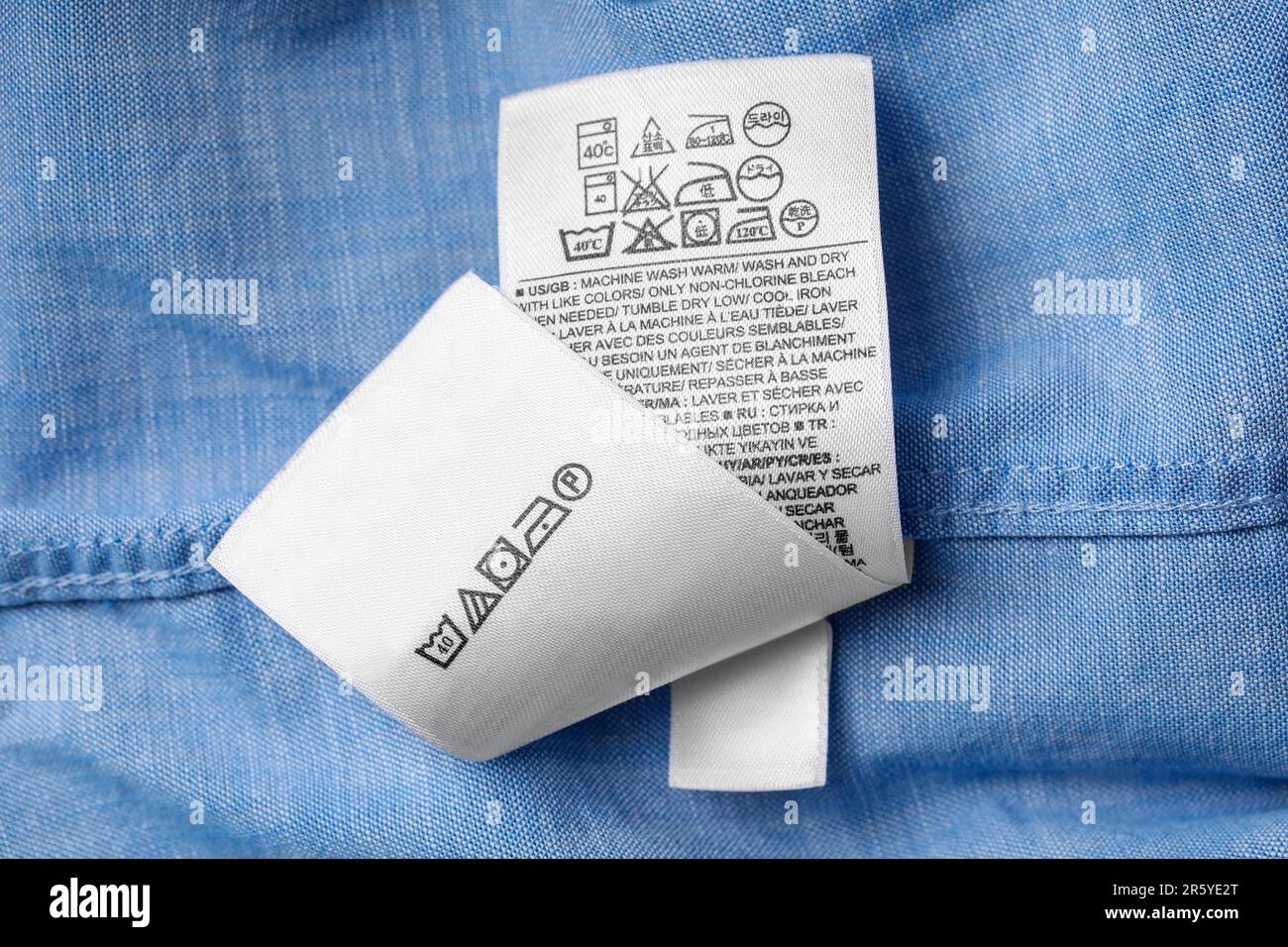 White clothing labels on light blue garment, top view Stock Photo - Alamy