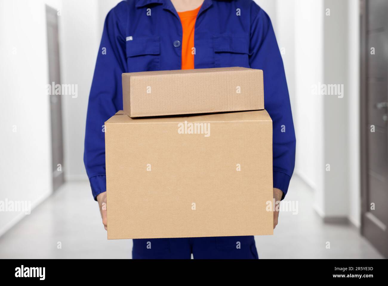 Courier with cardboard boxes in hallway, closeup Stock Photo - Alamy