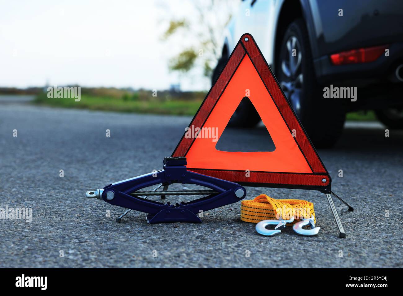Emergency warning triangle, towing strap and scissor jack near car ...