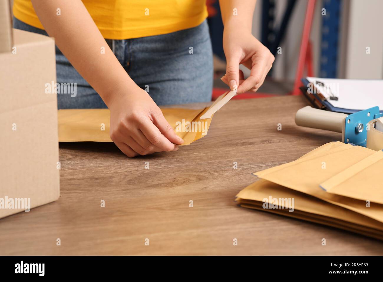 Post office worker with adhesive paper bag at counter indoors, closeup ...