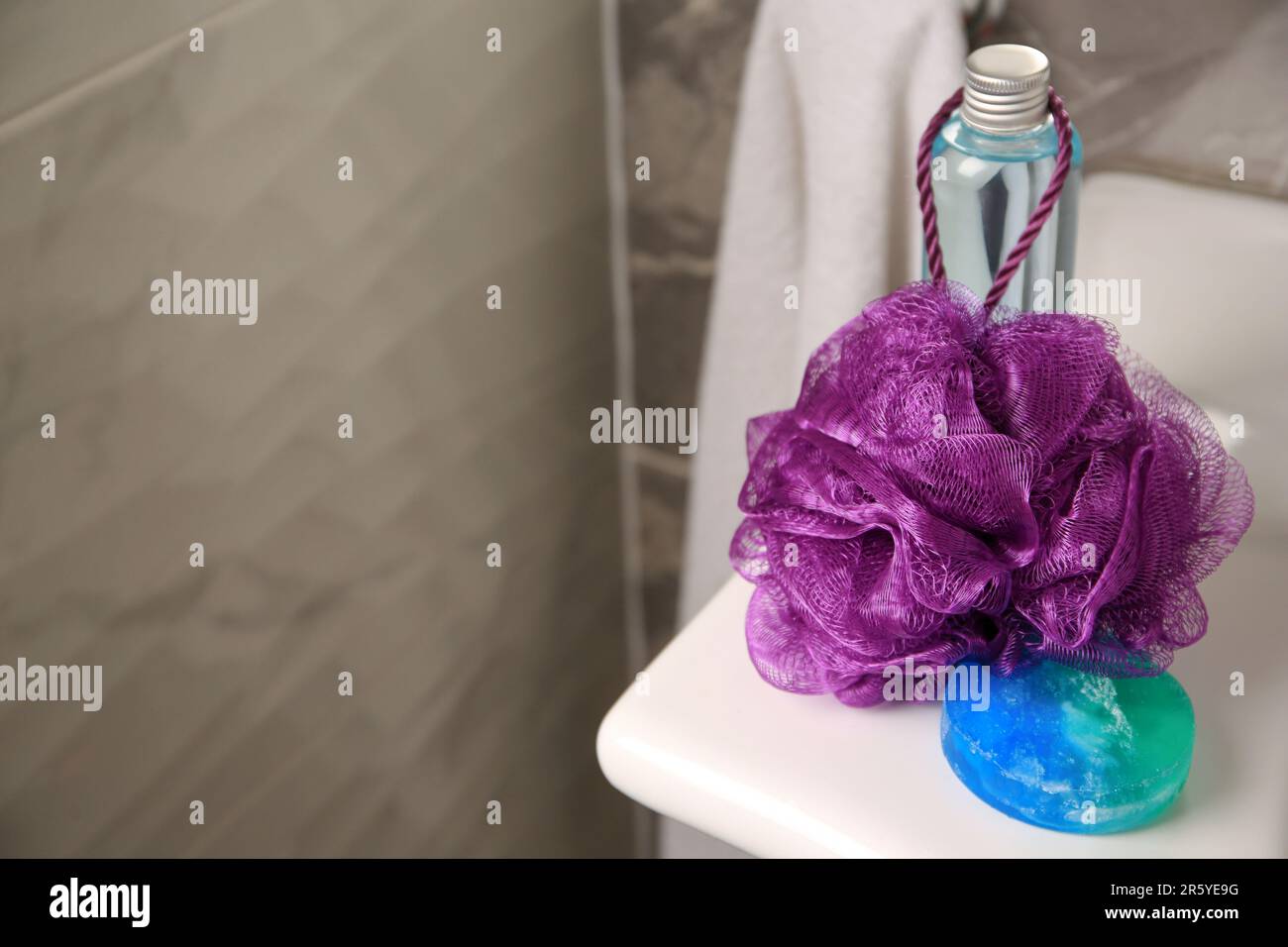 Purple shower puff and cosmetic products on sink in bathroom, space for ...