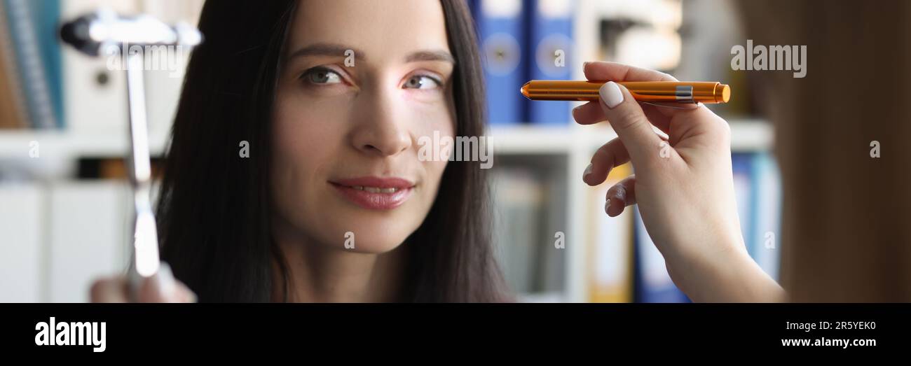 Doctor tests reflexes of eyes of young woman with lamp in medical ...