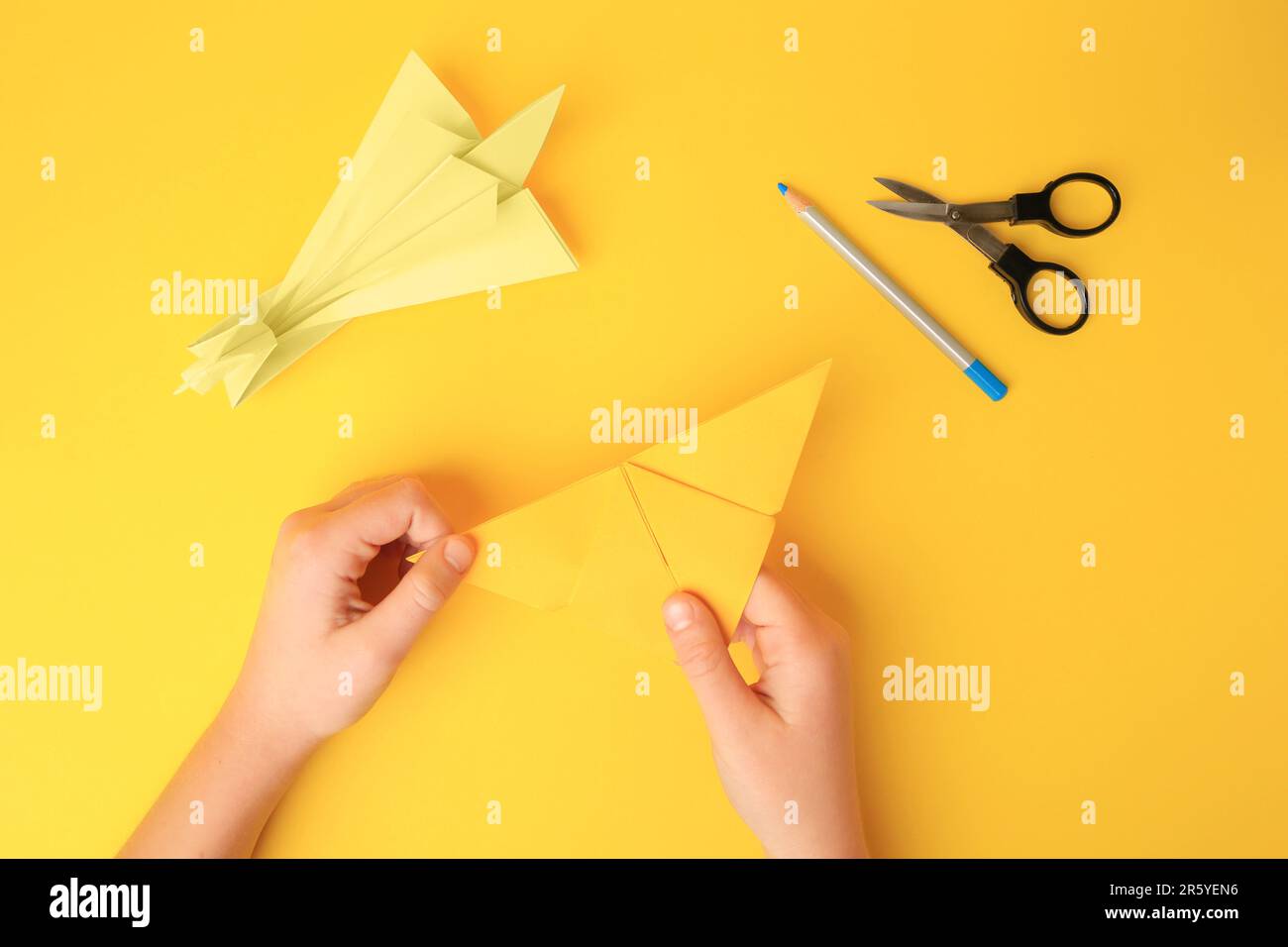 Origami art. Child holding paper figure on yellow background, closeup ...