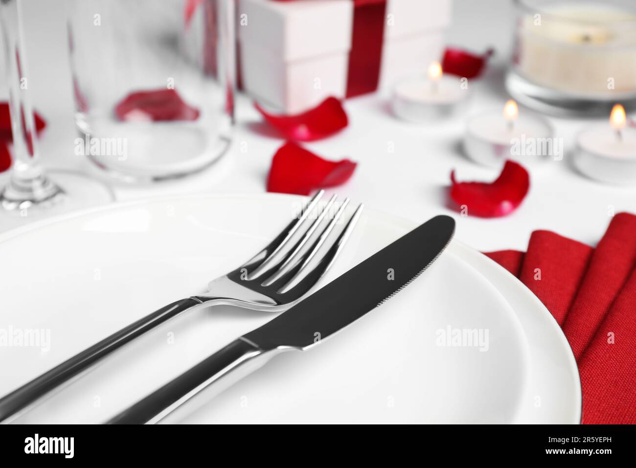 Beautiful table setting with rose petals on white table, closeup ...
