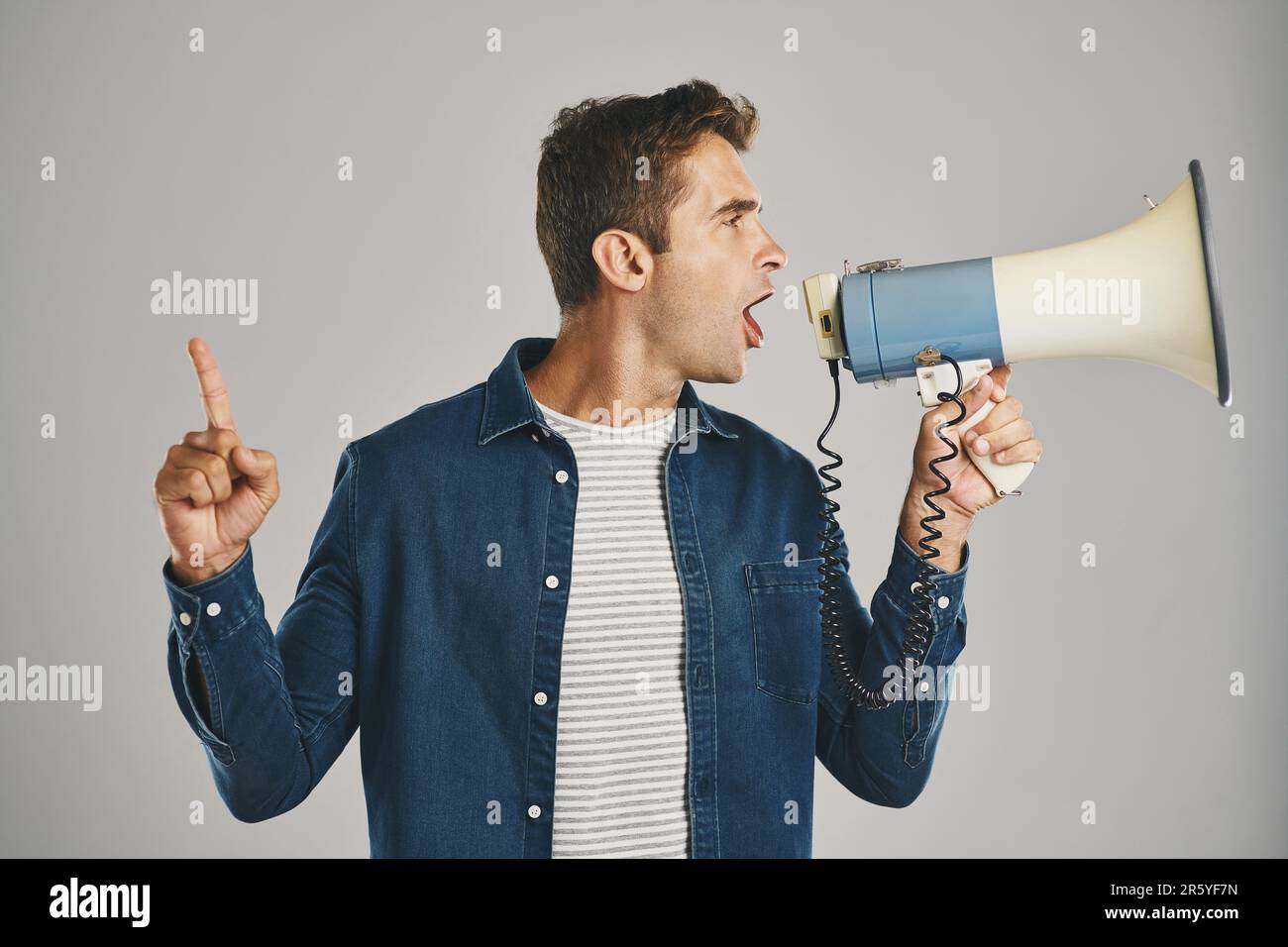 Leading the rally. Studio shot of a young man talking into a megaphone ...