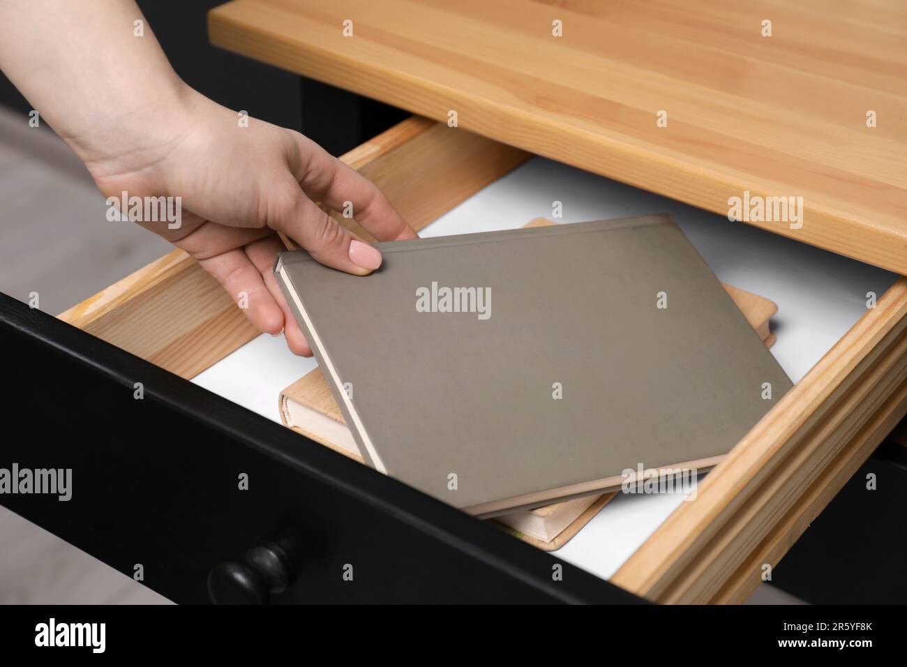 Woman putting notebook into desk drawer, closeup Stock Photo - Alamy
