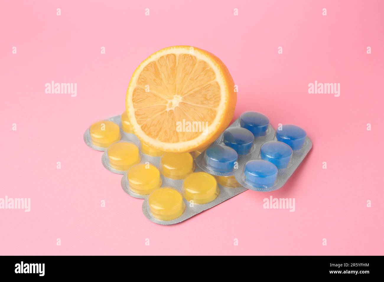 Blisters with cough drops and fresh lemon on pink background Stock ...