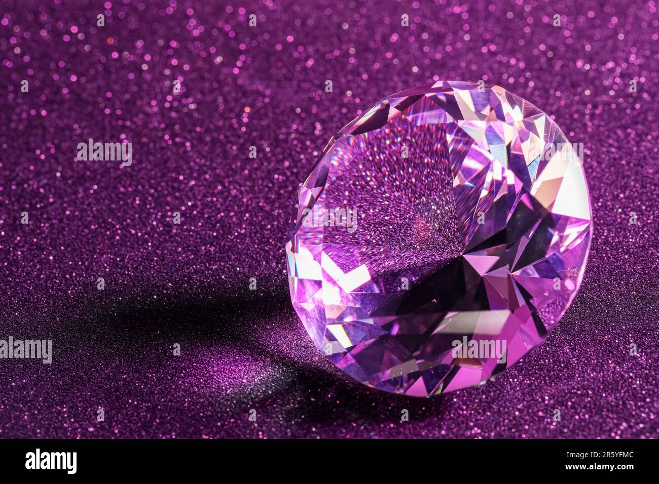 Beautiful shiny diamond on purple glitter background, closeup. Space ...