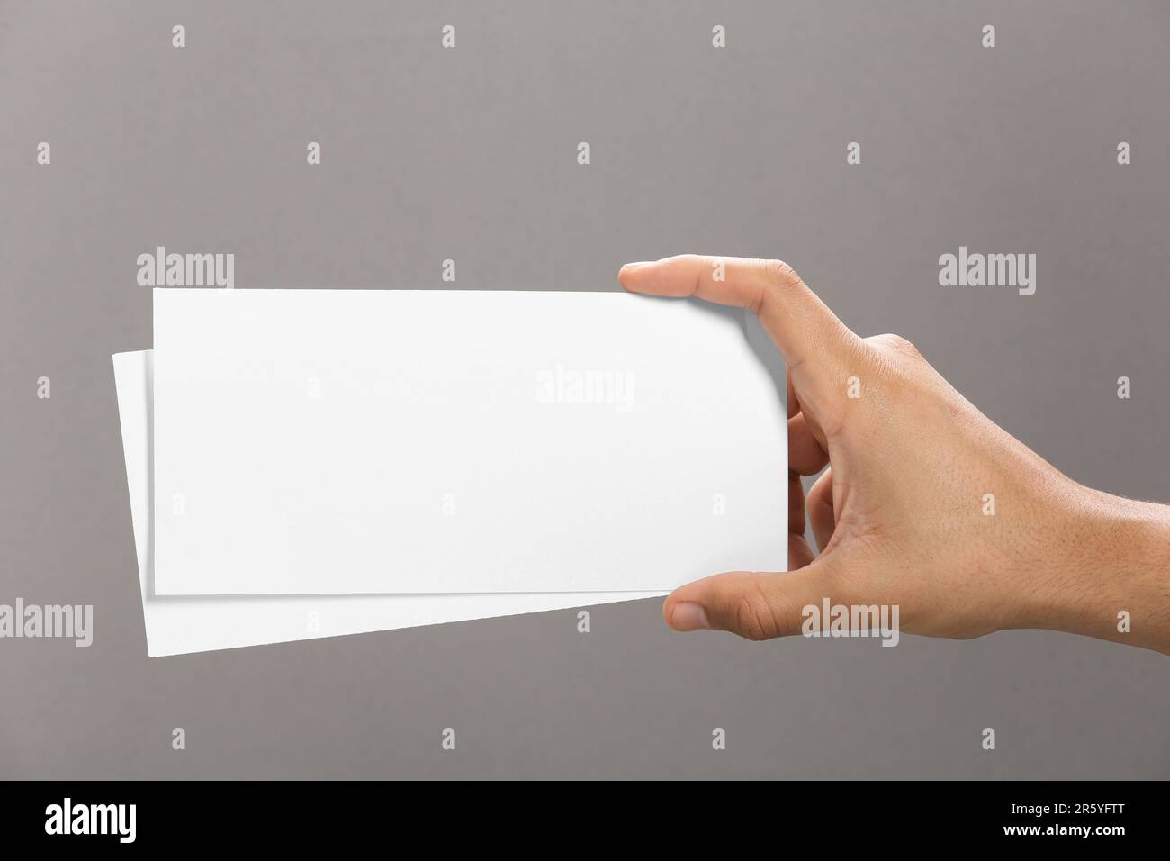 Man holding flyers on grey background, closeup. Mockup for design Stock ...