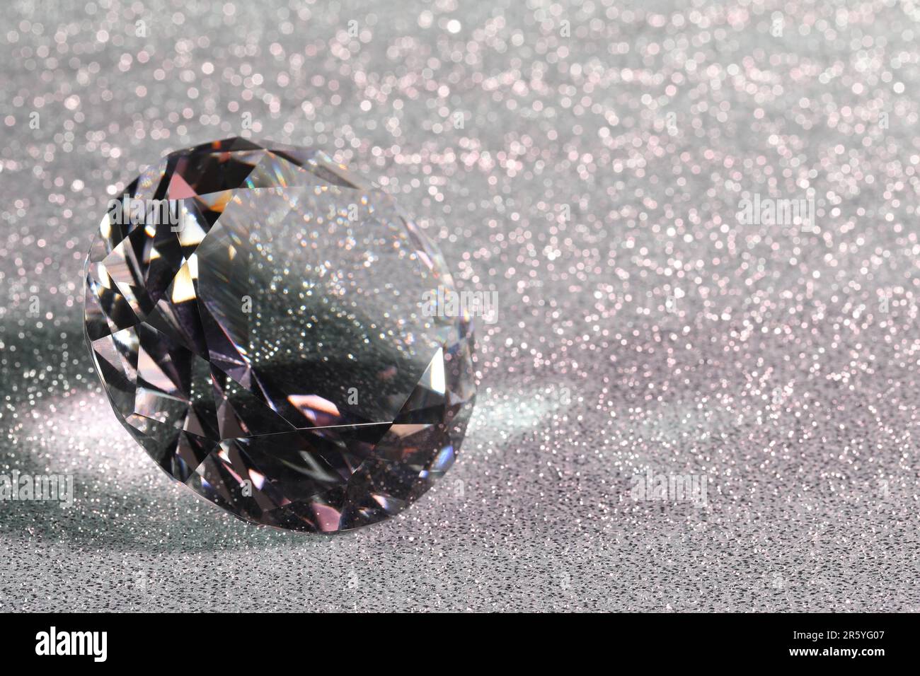 Beautiful dazzling diamond on silver glitter background, closeup. Space ...