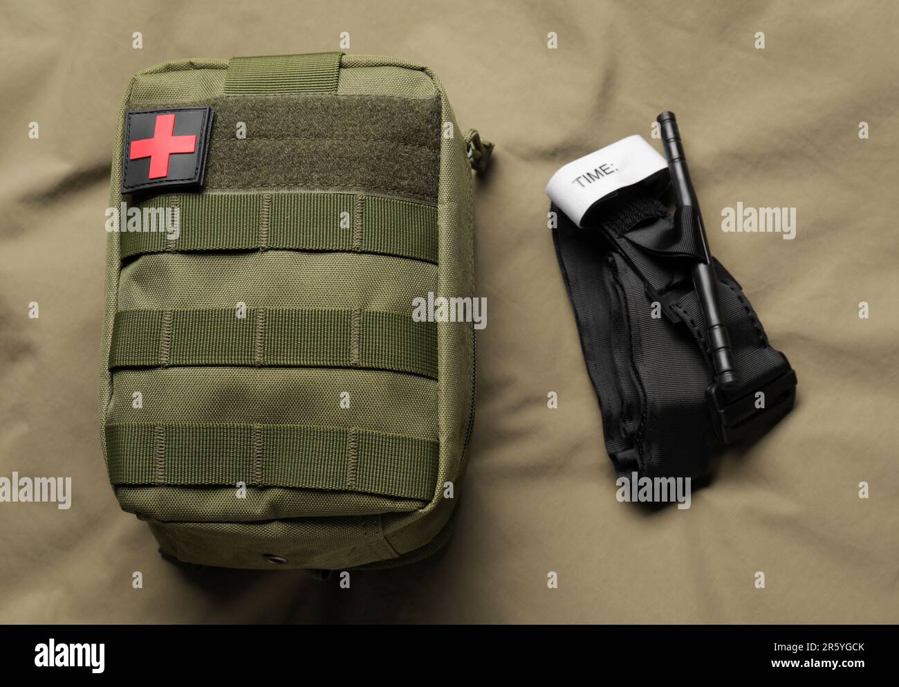 Military first aid kit and tourniquet on khaki fabric, flat lay Stock ...