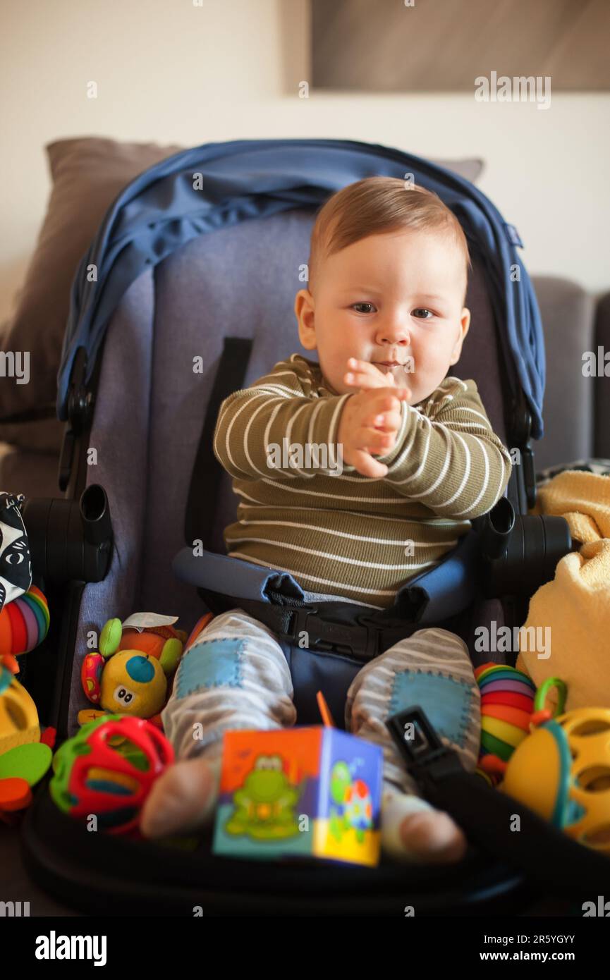 Portrait of cute baby boy in pram baby carriage, surrounded with ...