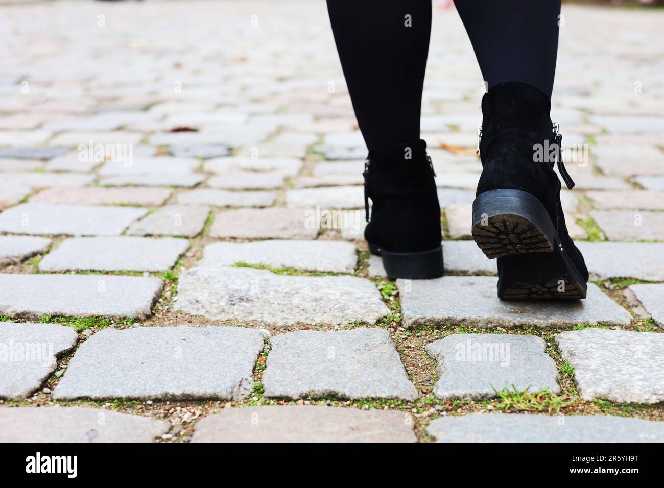 Close-up of a young woman's legs on a paved street in the old town ...