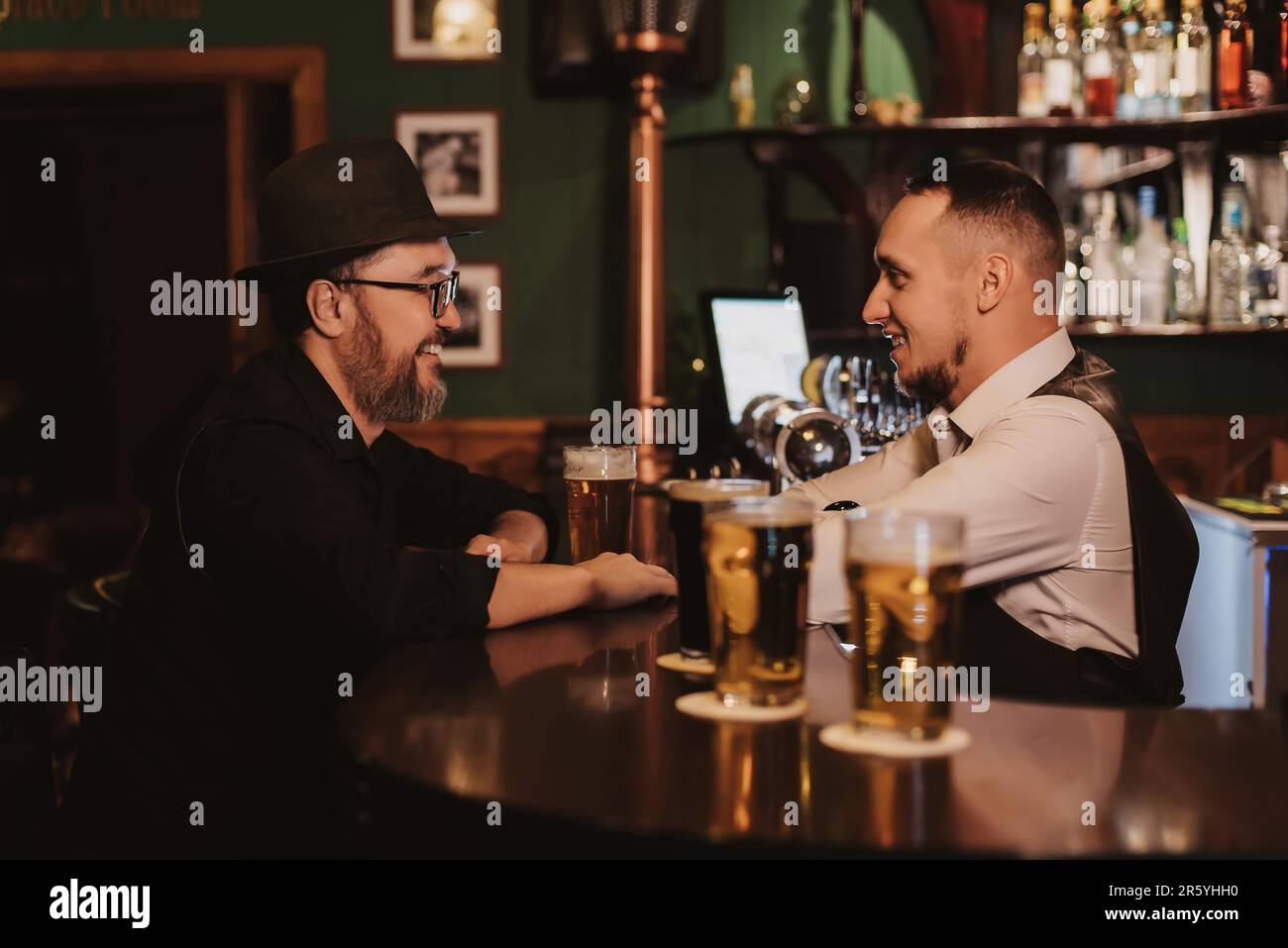 man has fun chatting with a bartender at bar counter with a glass of ...