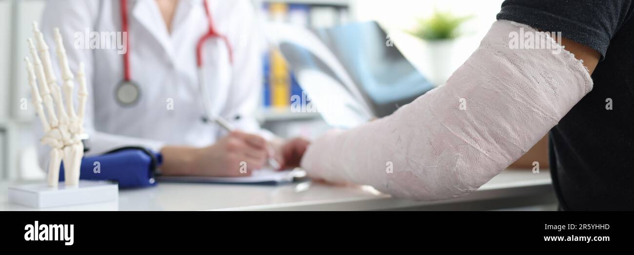 Patient with plaster cast on broken arm consults doctor in hospital ...