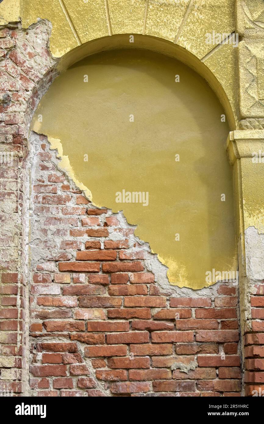 Partially destroyed plastered old brick wall with an arched niche and ...