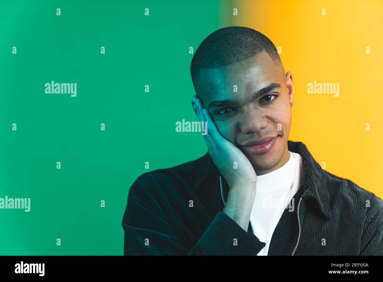 Handsome black man posing with one hand on his cheek against colorful ...