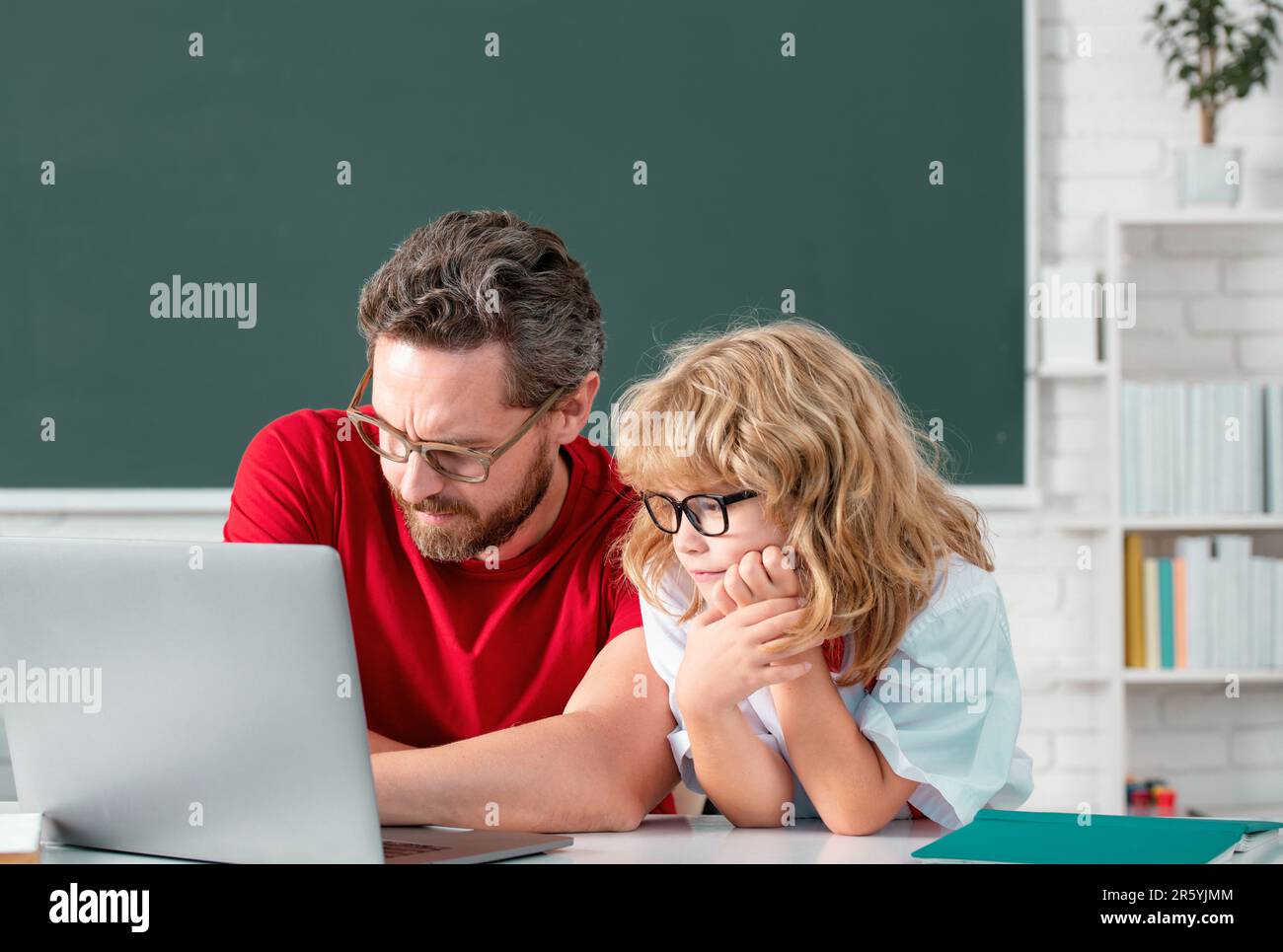 School teacher and child pupil learning at laptop computer, studying ...
