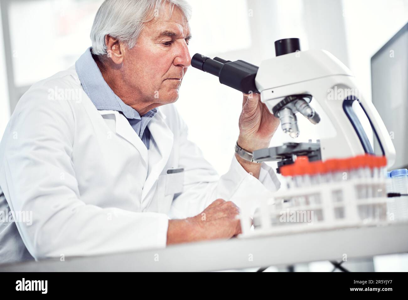 Pay attention to detail. a focused elderly male scientist looking ...