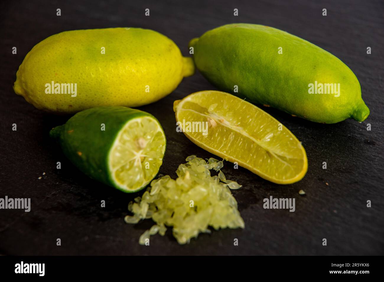 Finger lime, cut in half, on a dark surface Stock Photo - Alamy