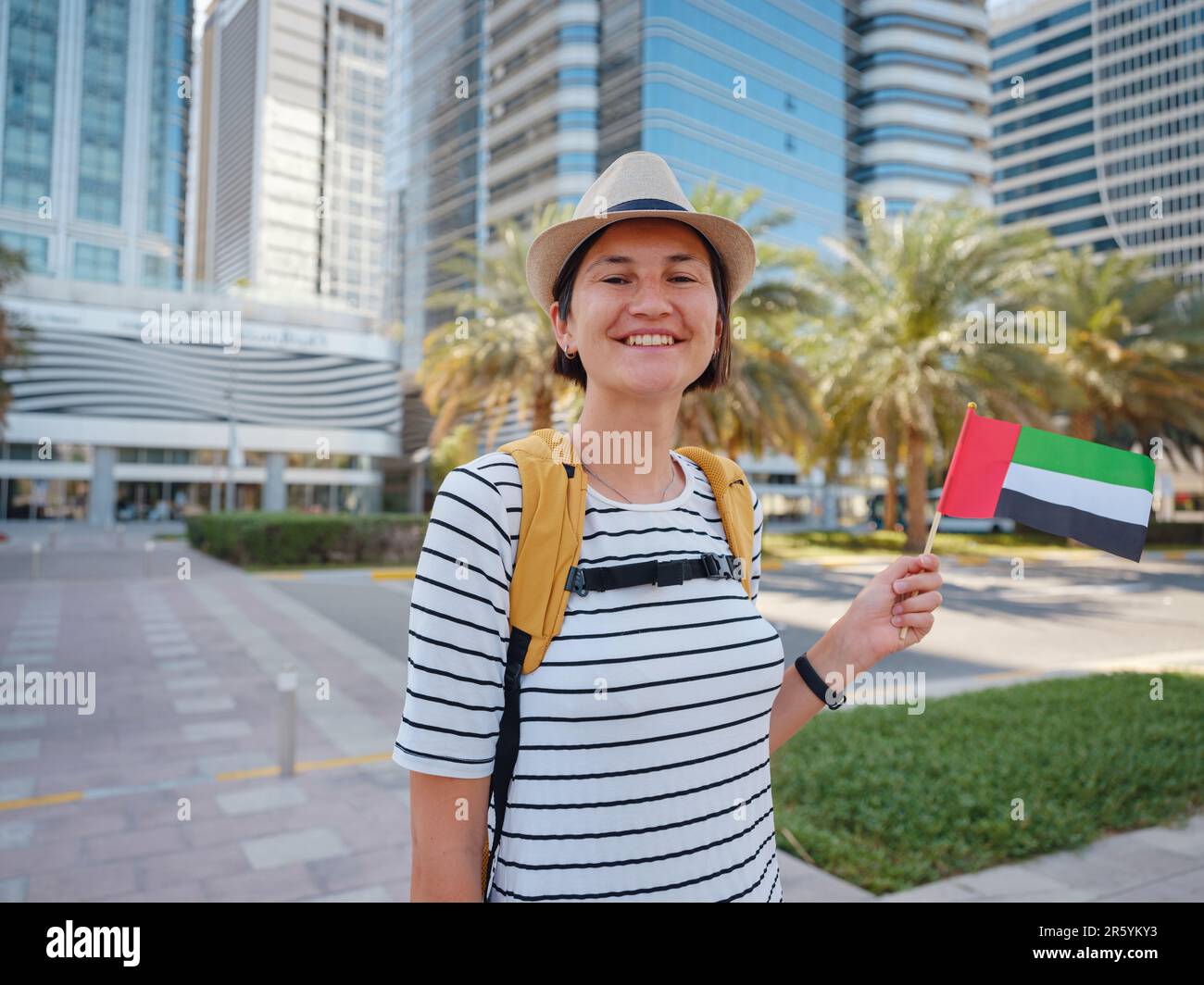 Happy young asian female traveler with backpack and hat with UAE flag ...