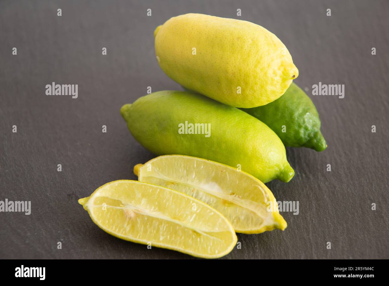 Finger lime, cut in half, on a dark surface Stock Photo - Alamy
