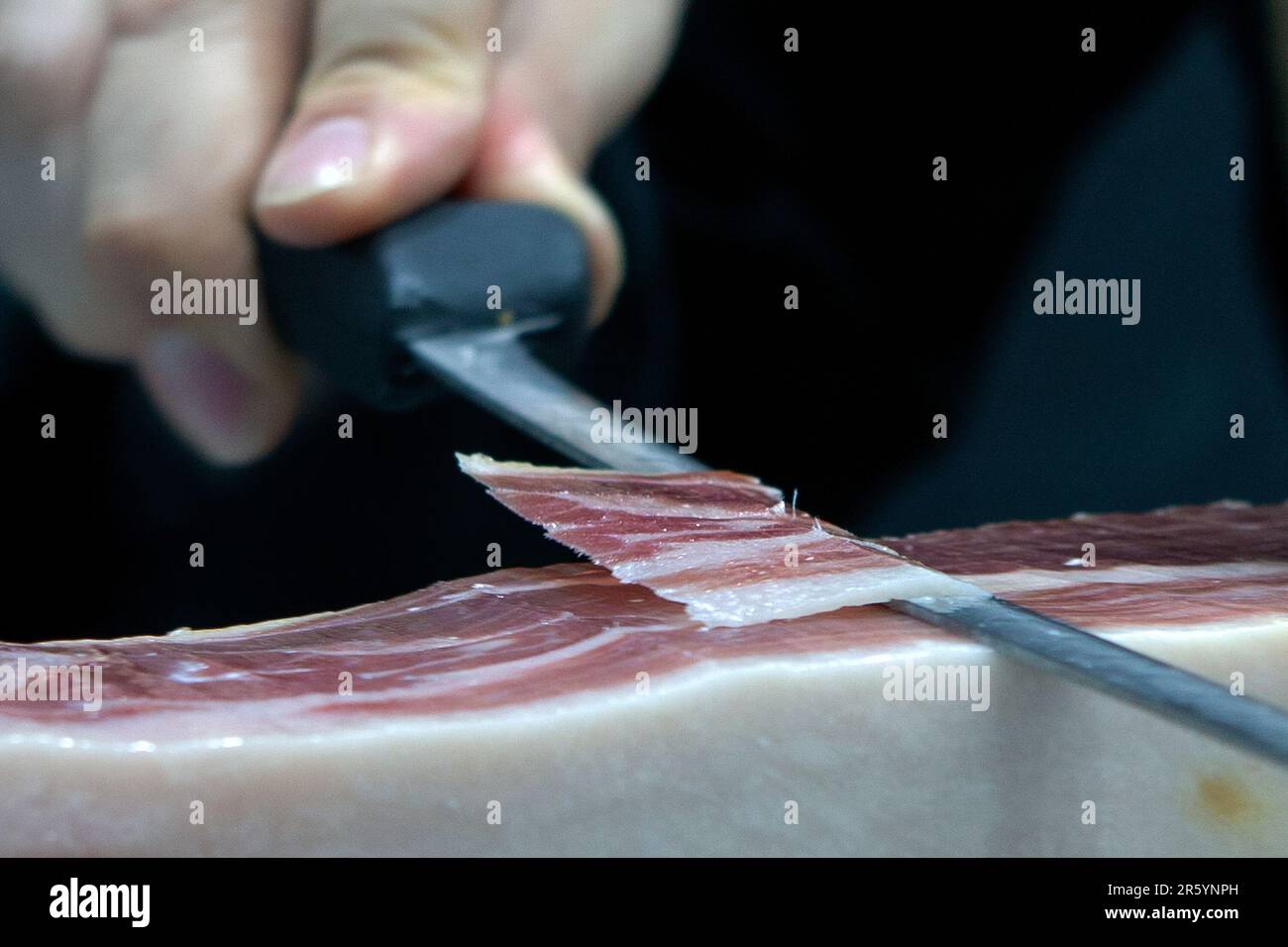 chef who cuts a slice of ham, of excellent quality, with the knife ...