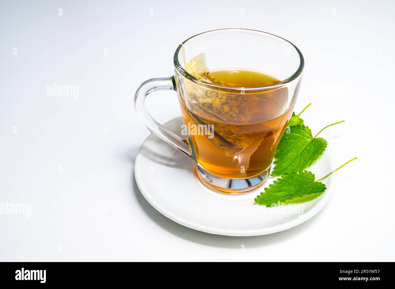 Nettle herbal tea in a transparent cup, with a sachet immersed in water ...
