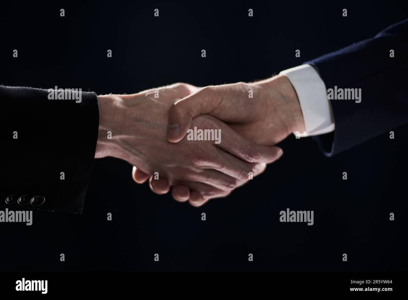 Handshake - Hand on a black background. success concept Stock Photo - Alamy