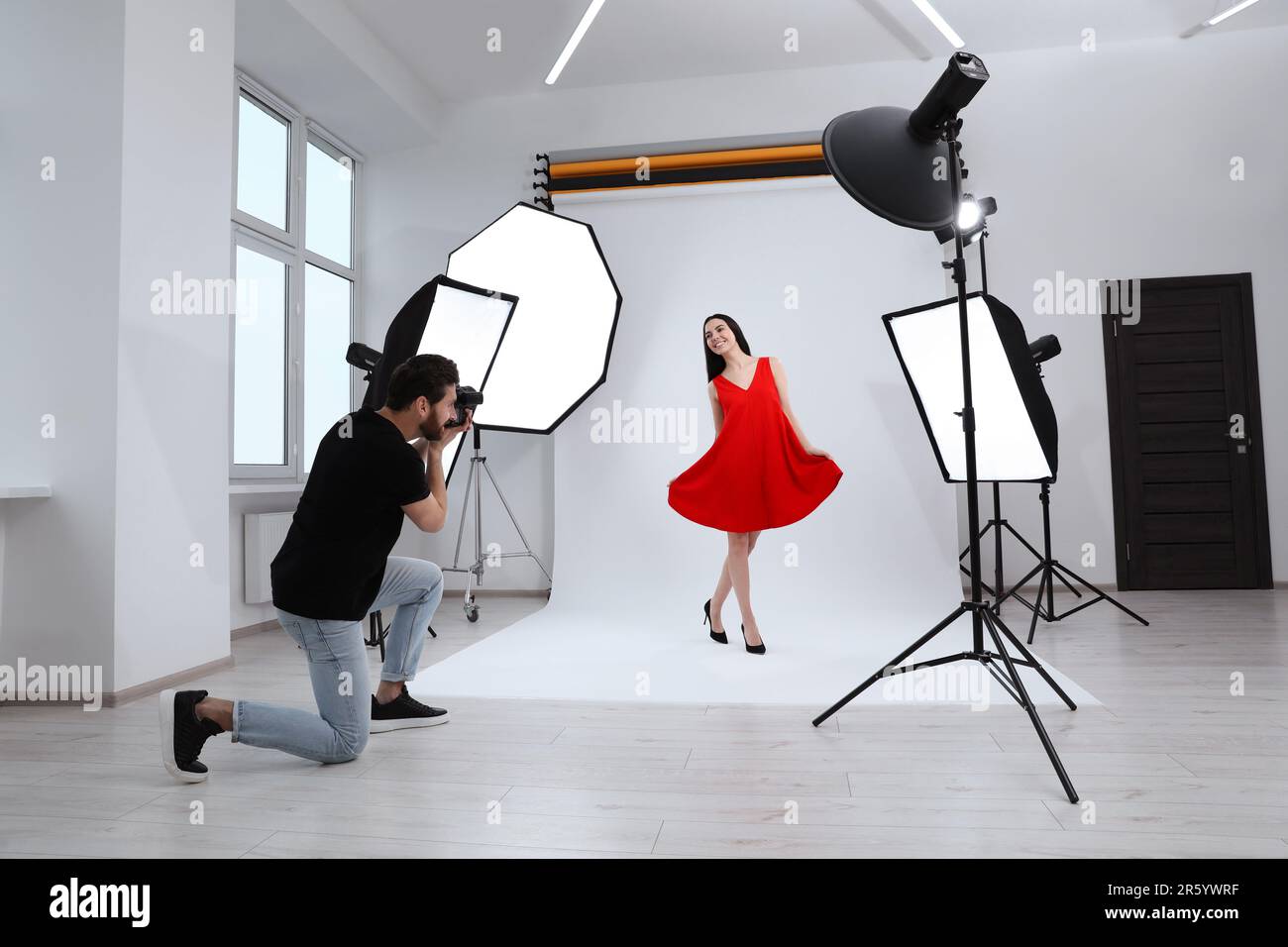 Beautiful young model posing for professional photographer in studio ...