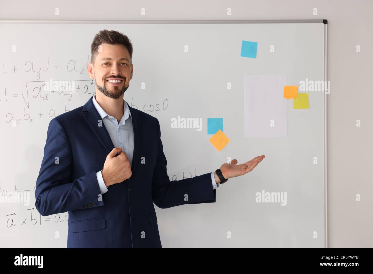 Happy teacher explaining mathematics at whiteboard in classroom Stock ...