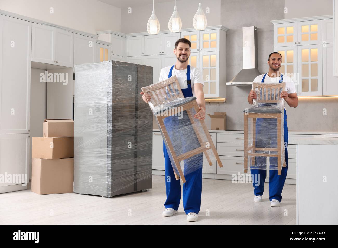 Male movers carrying chairs in new house Stock Photo - Alamy