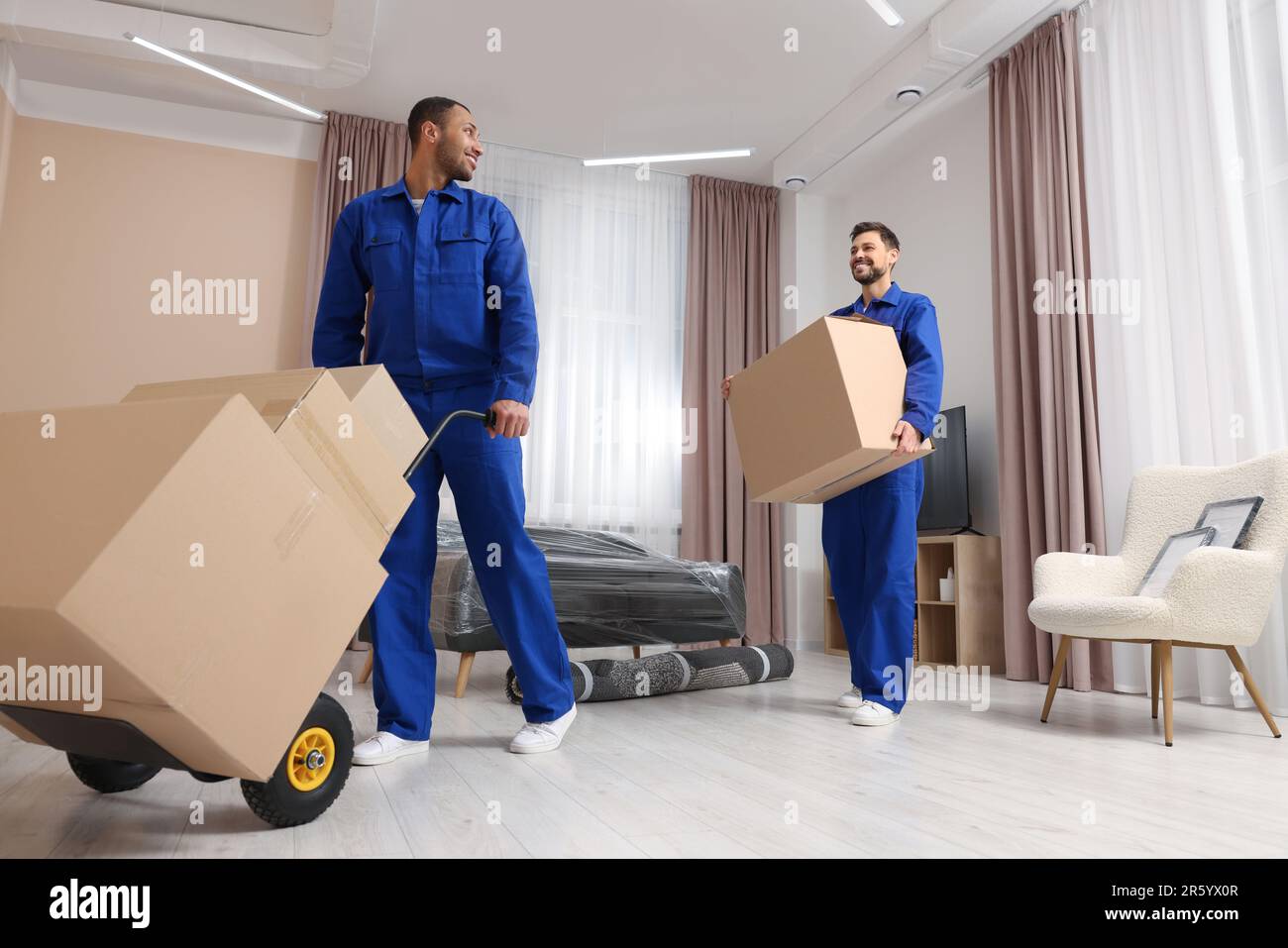 Male movers with cardboard boxes in new house Stock Photo - Alamy