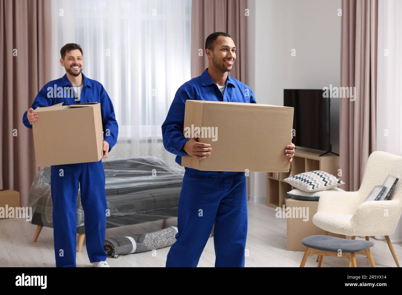 Male movers with cardboard boxes in new house Stock Photo - Alamy