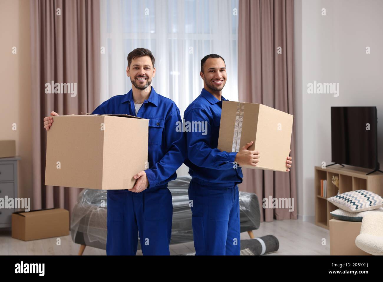 Male movers with cardboard boxes in new house Stock Photo - Alamy