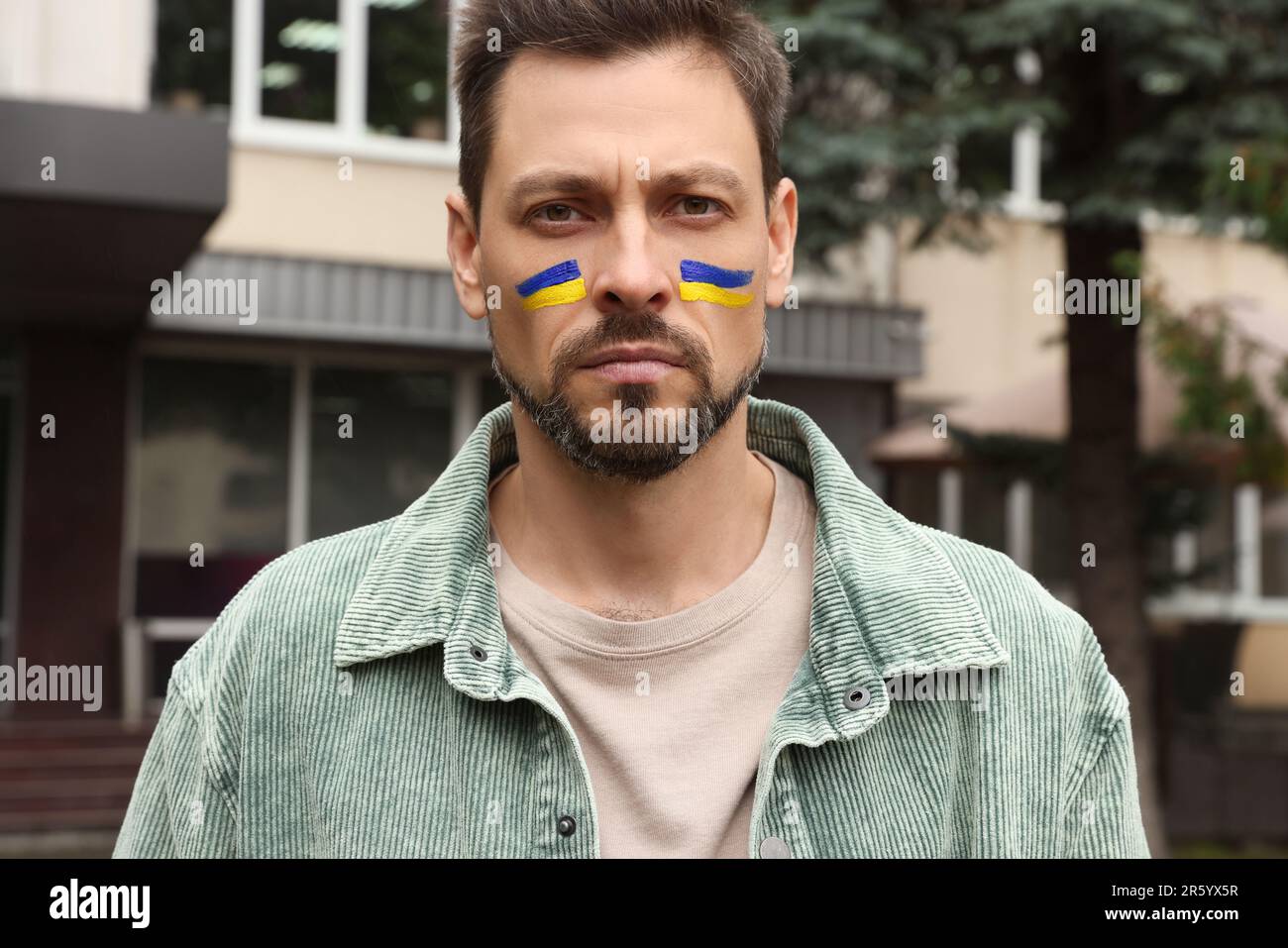 Man with drawings of Ukrainian flag on face outdoors Stock Photo - Alamy