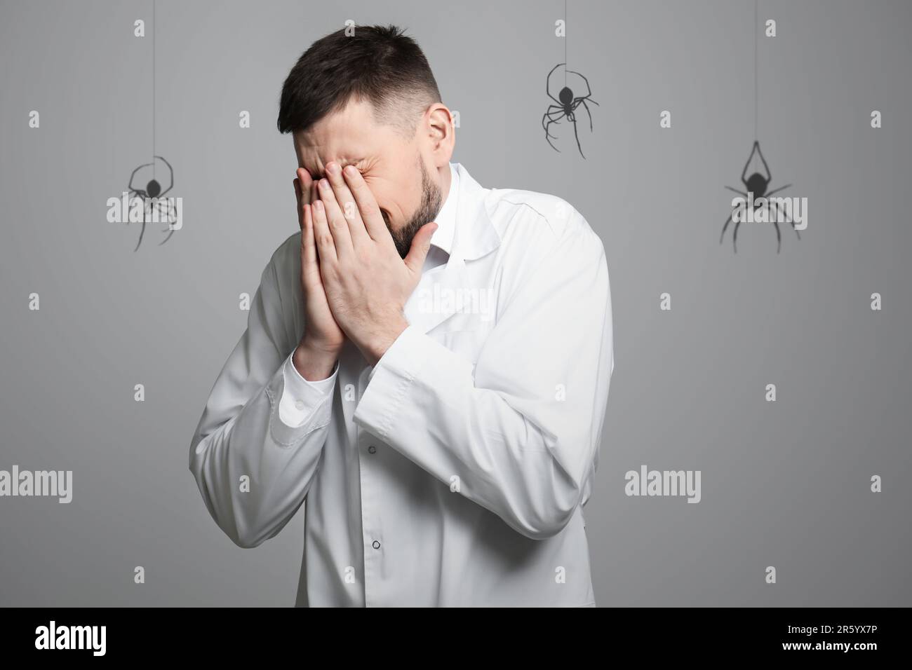 Scared man suffering from panic attack on grey background. Shadows of ...