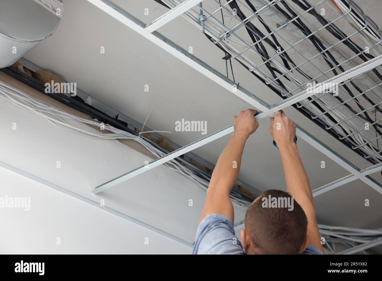 Worker installing metal frame indoors, closeup. Suspended ceiling Stock ...