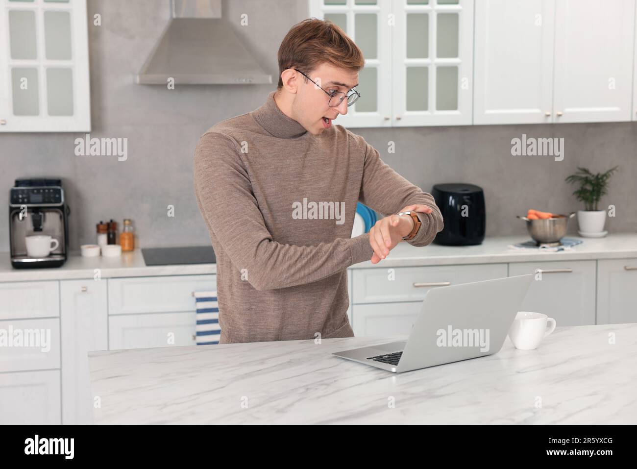 Emotional young man checking time in kitchen. Being late Stock Photo ...