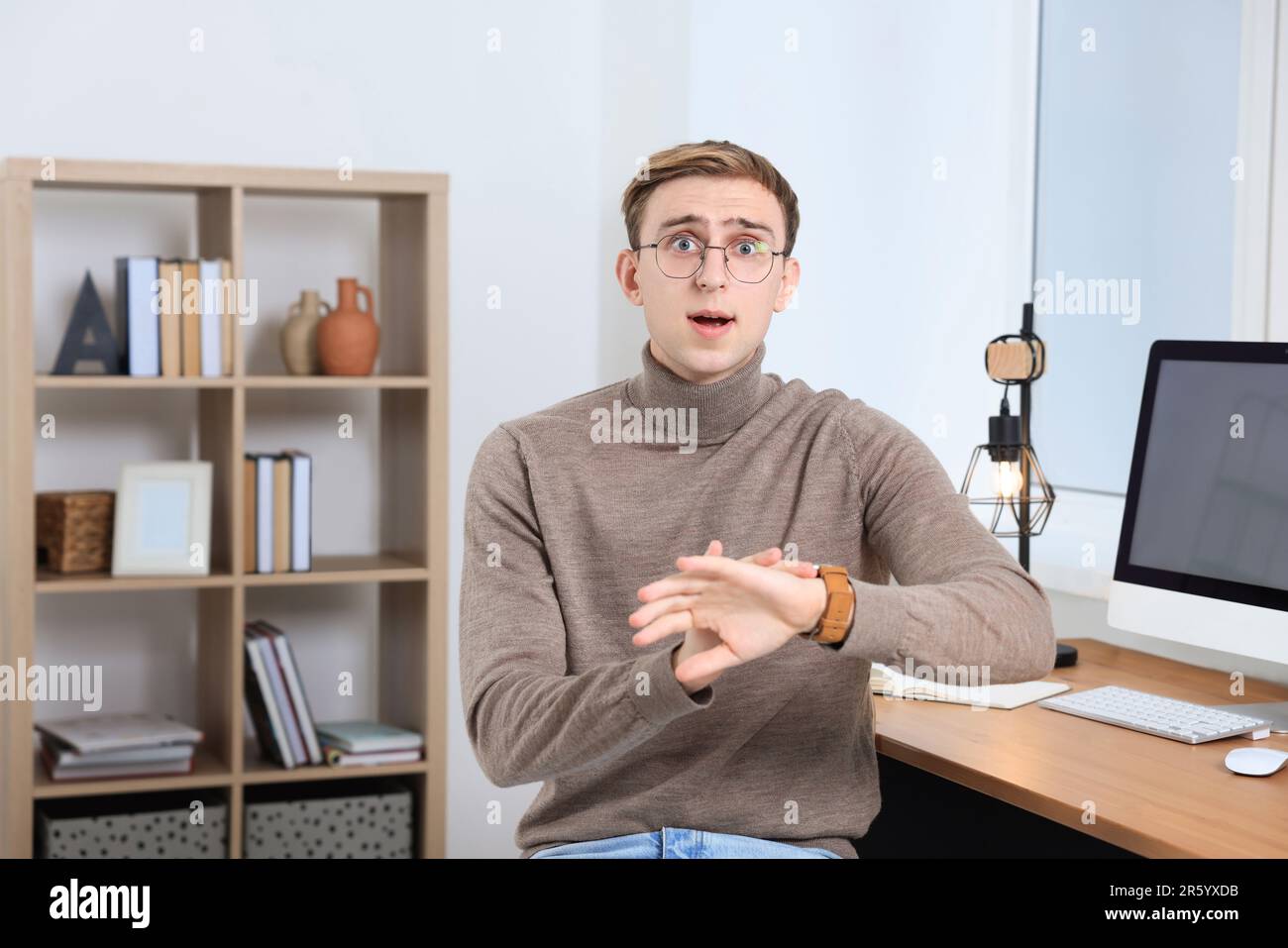 Emotional young man checking time in office. Being late Stock Photo - Alamy