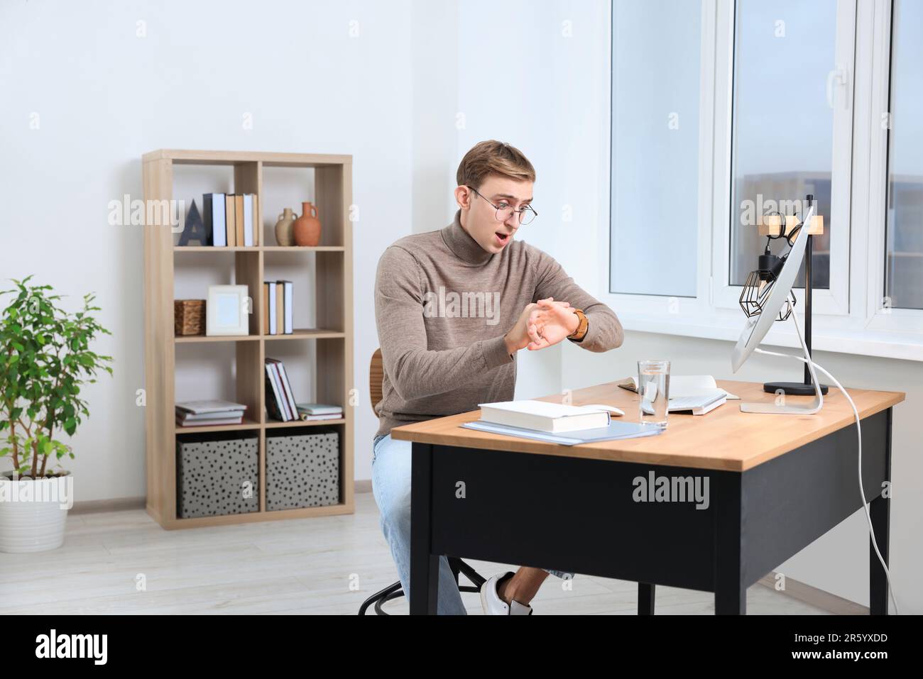 Emotional young man checking time in office. Being late Stock Photo - Alamy