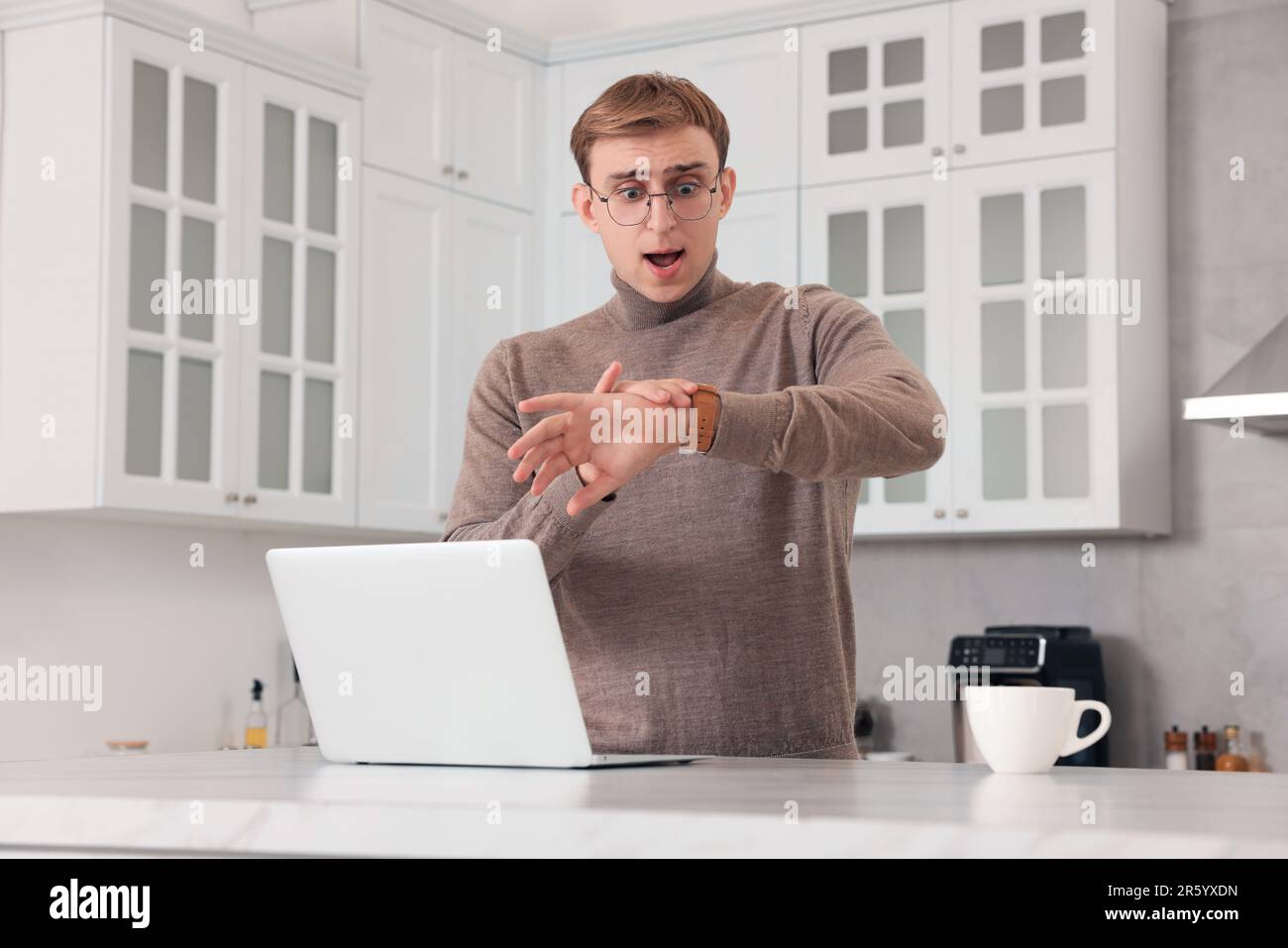 Emotional young man checking time in kitchen. Being late Stock Photo ...