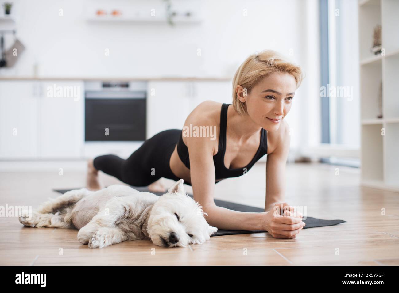 Peaceful blonde lady in black activewear doing yoga practice while ...