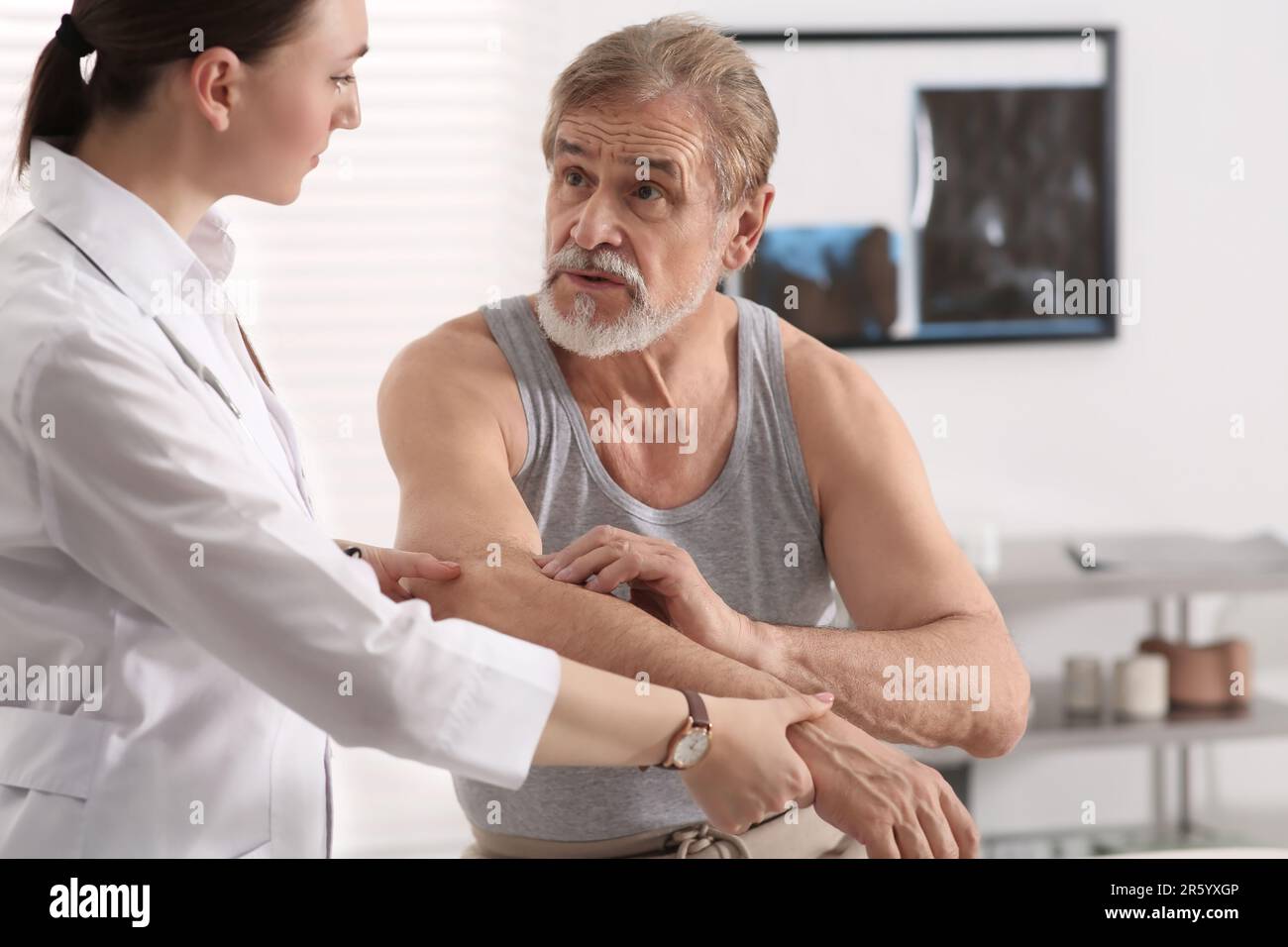 Orthopedist examining patient with injured arm in clinic Stock Photo ...