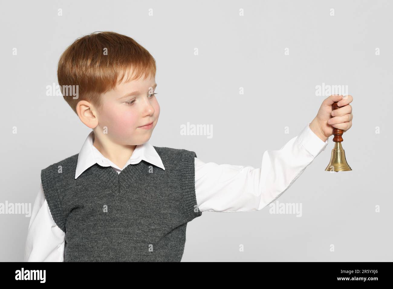 Pupil with school bell on light grey background Stock Photo - Alamy