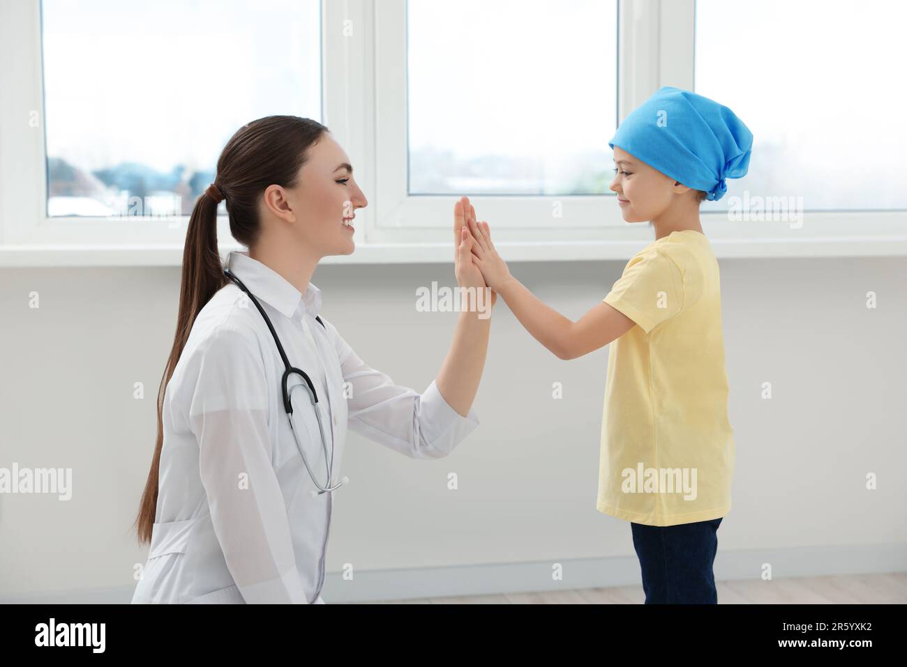 Childhood cancer. Doctor and little patient giving high five in ...
